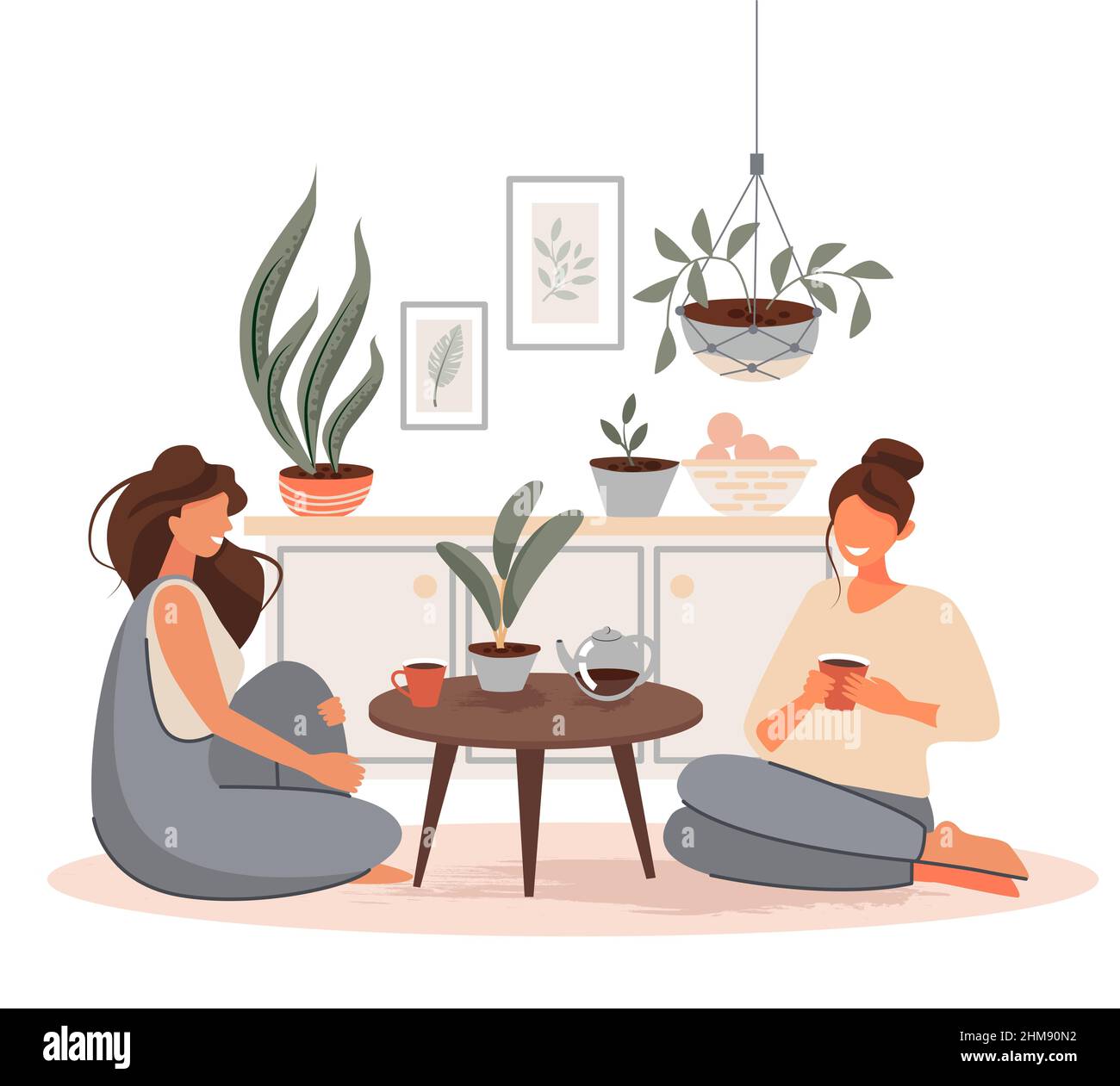 Two girls are drinking tea and talking while sitting on the floor ...