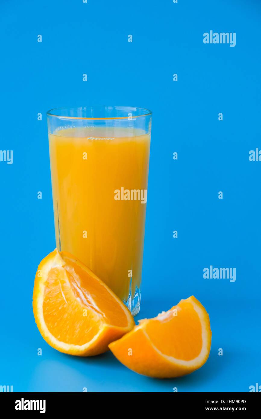 Glass bottle of fresh squeezing Orange juice with sliced fruits on blue ...