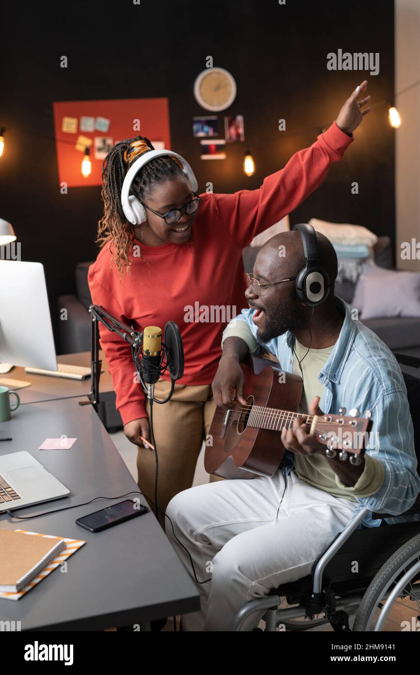 Happy African man with disability playing guitar and singing a song ...