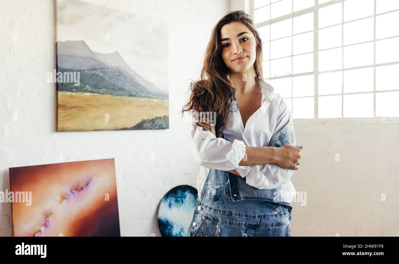 Cheerful painter standing in front of her paintings. Female artist ...