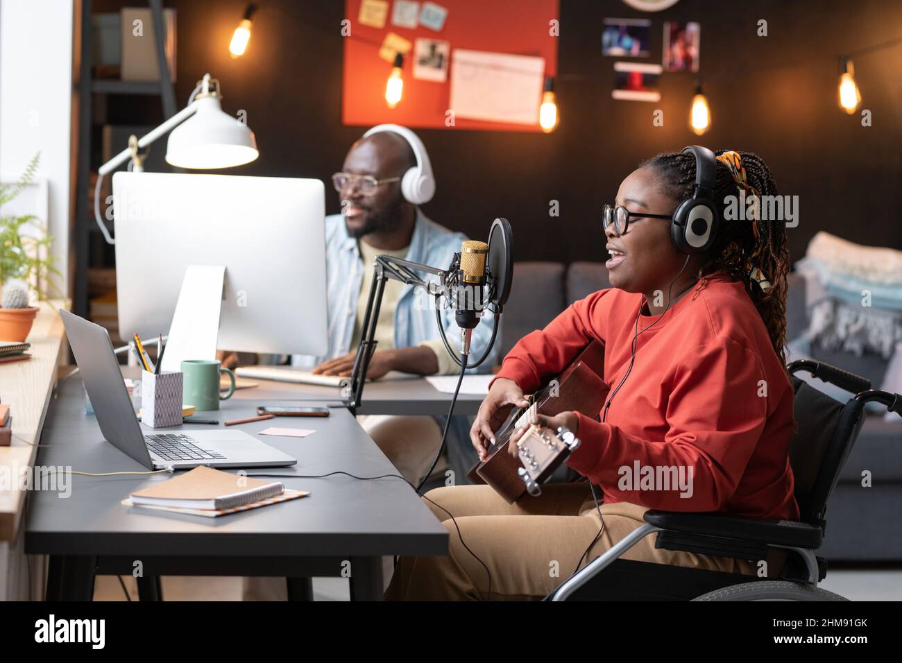 African woman with disability sitting on wheelchair playing guitar and ...