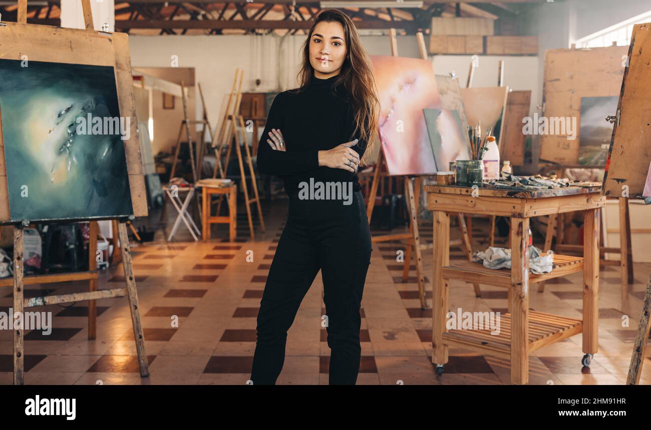 Professional painter standing in her workshop with her artwork behind ...