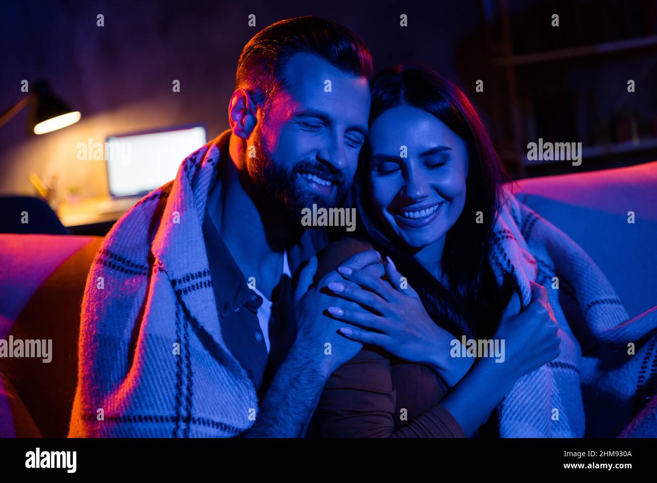Photo of loving supportive spouses guy cuddle lady cover plaid blanket sit couch in evening ...