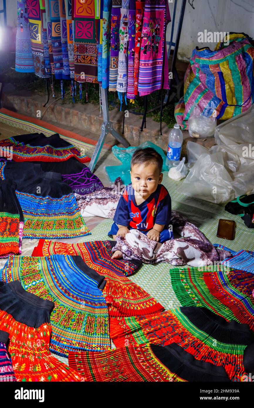 Cute local baby boy sits in a stall selling fabrics and souvenirs in ...