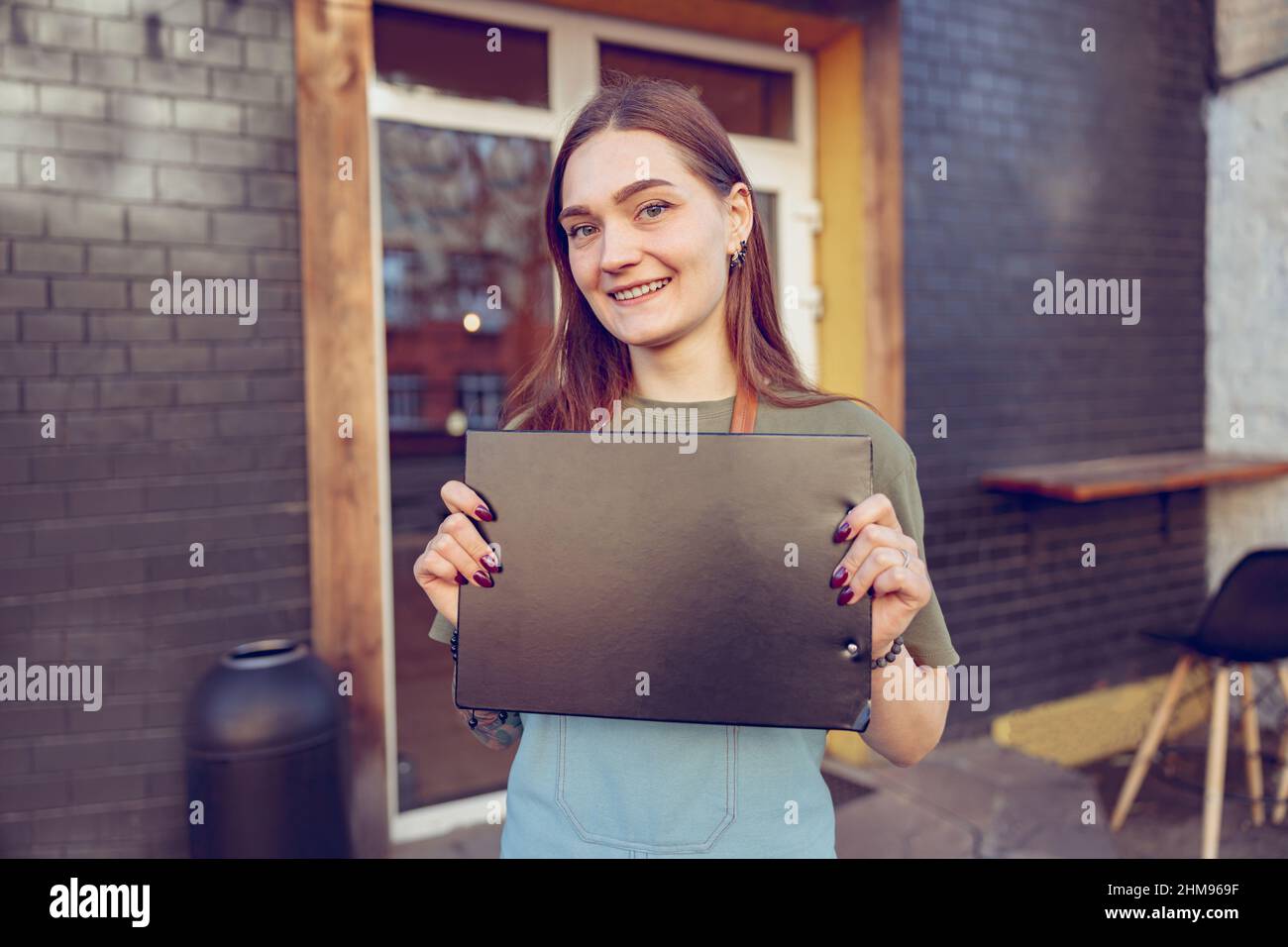 Cheerful female barista holding clipboard outside coffee shop Stock ...