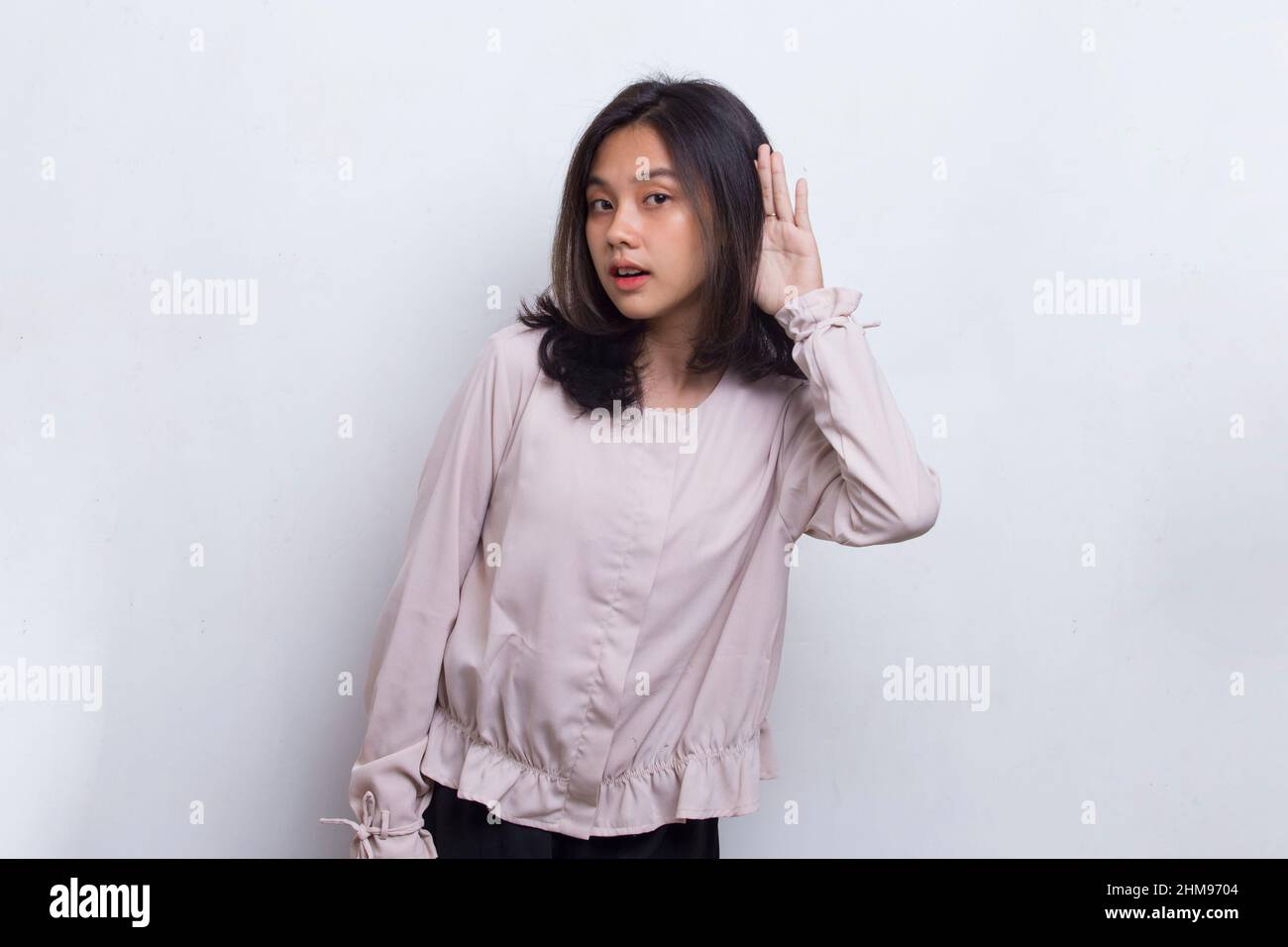 Young beautiful asian woman with hand over ear listening an hearing to ...