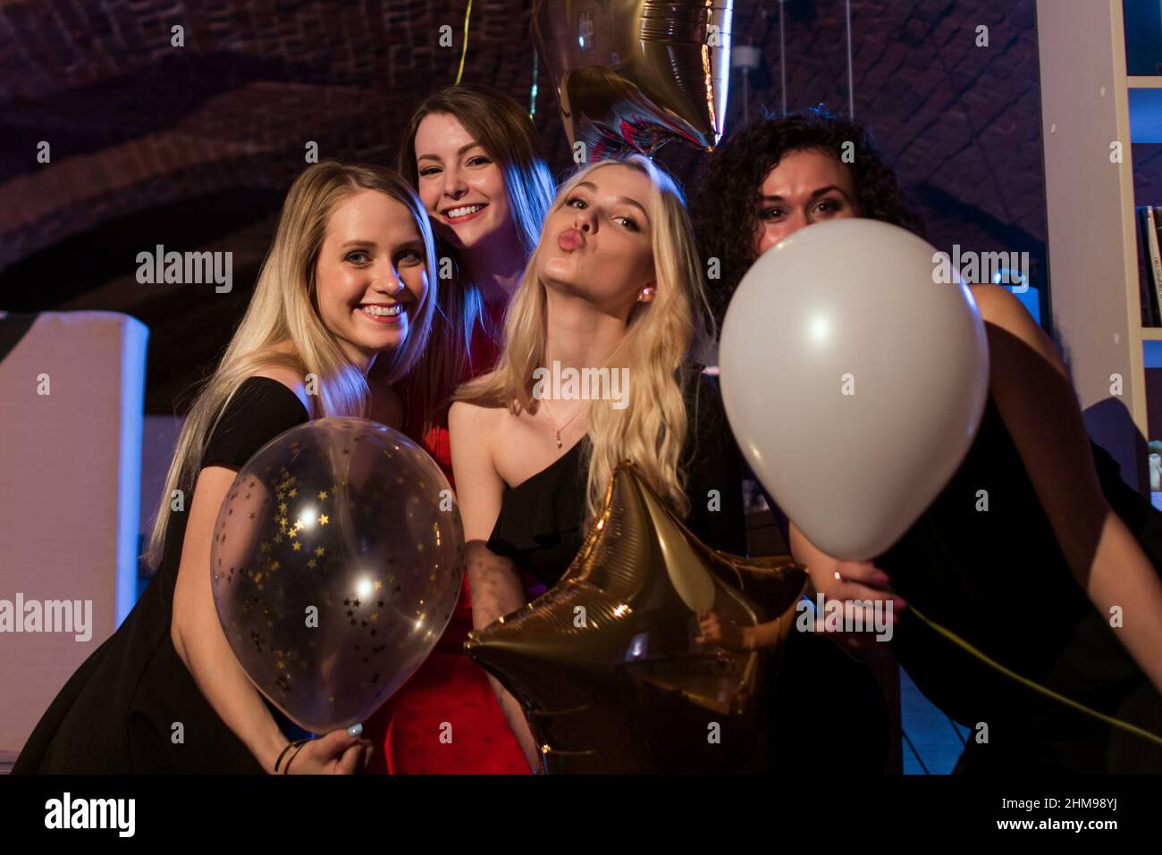 Four beautiful young Caucasian women holding balloons having night out ...