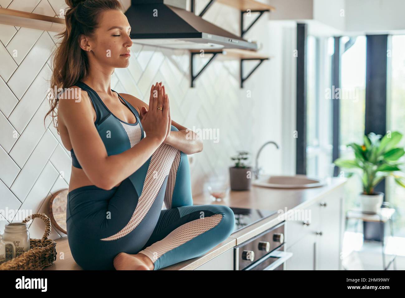 Girl in the kitchen meditating practicing yoga Stock Photo - Alamy