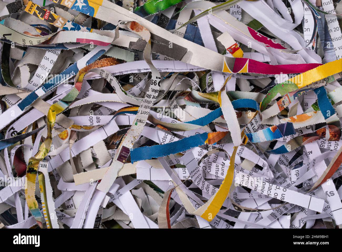 Full frame macro shot of colorful shredded strips of paper with text on ...