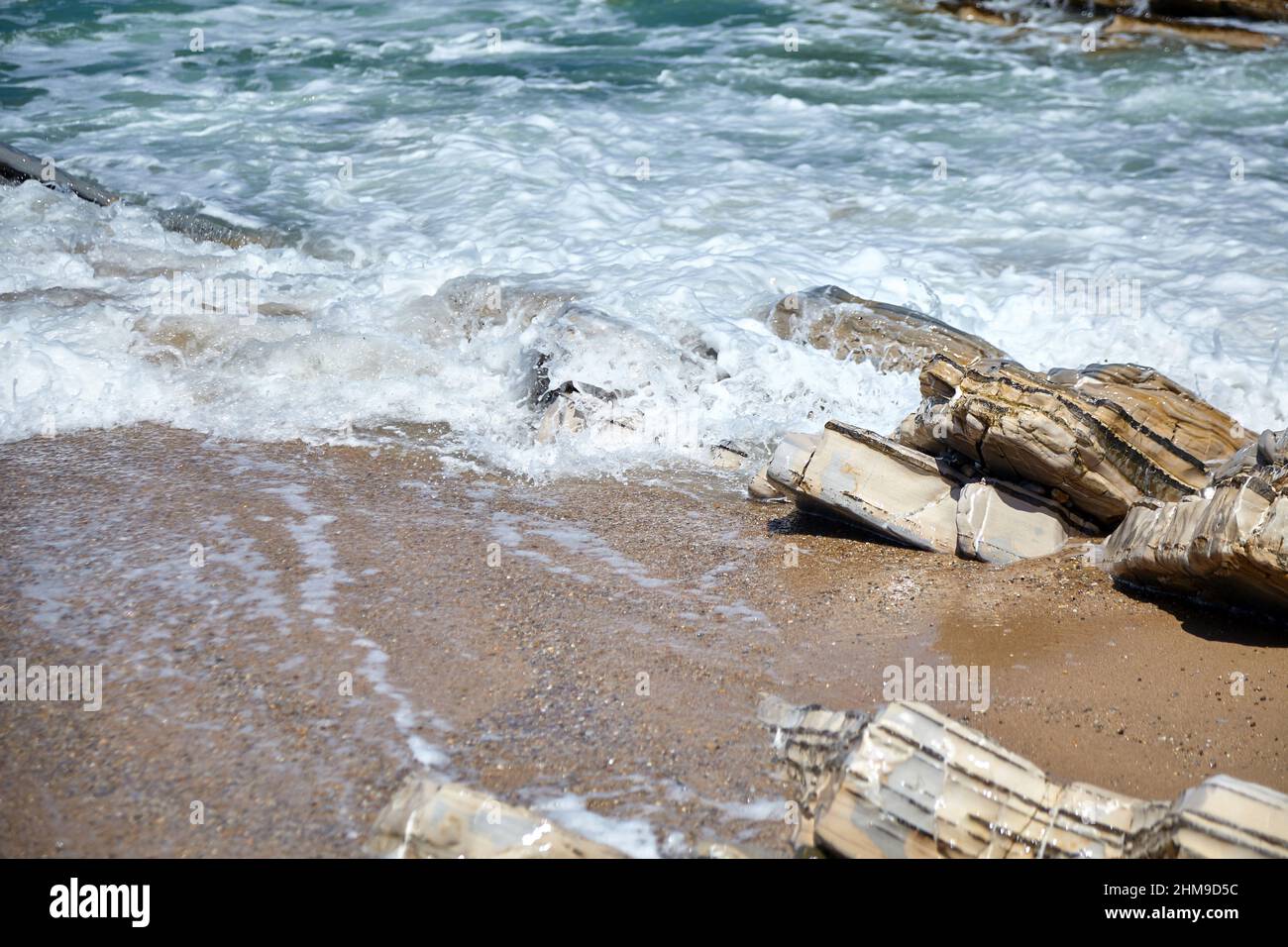Sandy-pebble beach and large stones. Wet sand, wave, sea water and ...