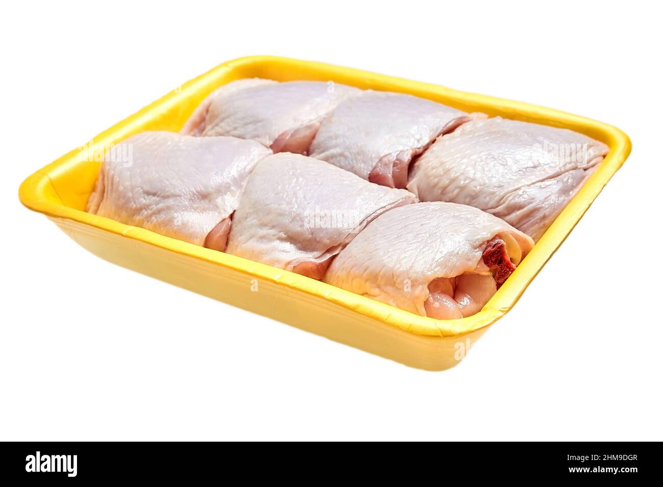 Raw chicken thighs in a yellow tray isolated on white background Stock ...