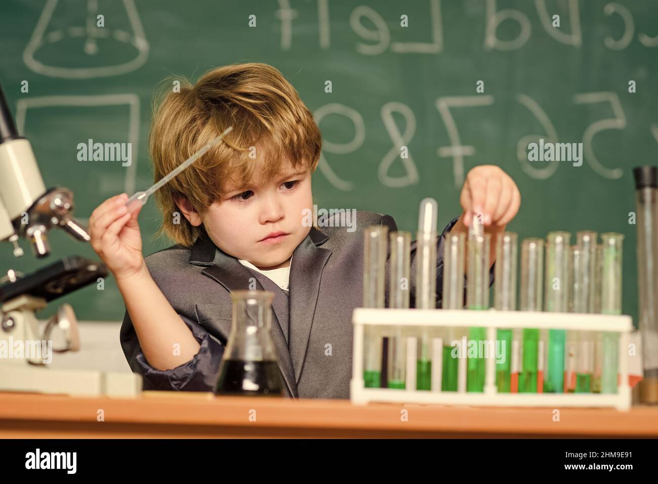 Wunderkind experimenting with chemistry. Boy test tubes liquids ...