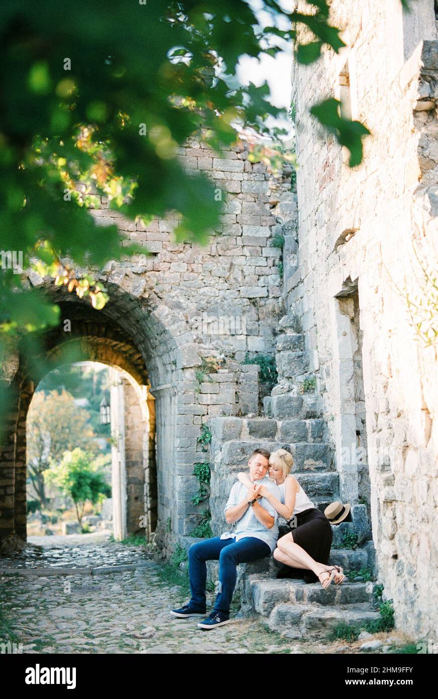 Woman hugs a man while sitting on the stone steps of the castle Stock ...