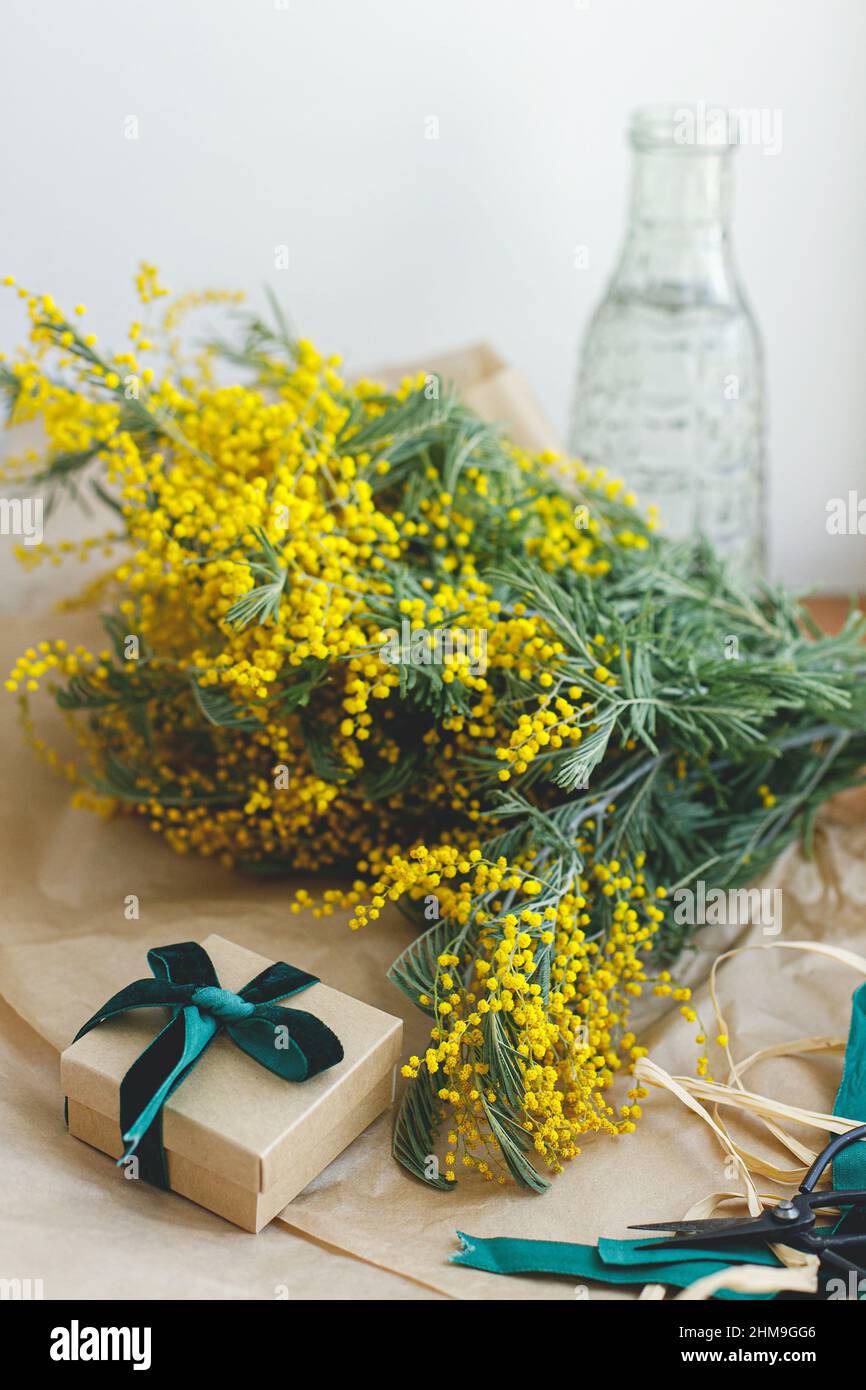 Stylish mimosa bouquet and gift box on wooden background. Happy womens ...