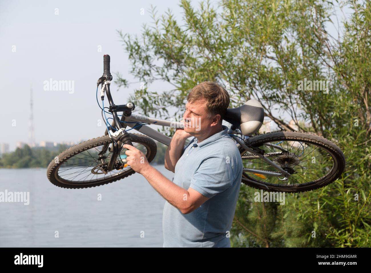 frustrated adult man carries a broken bicycle on his shoulder Stock ...