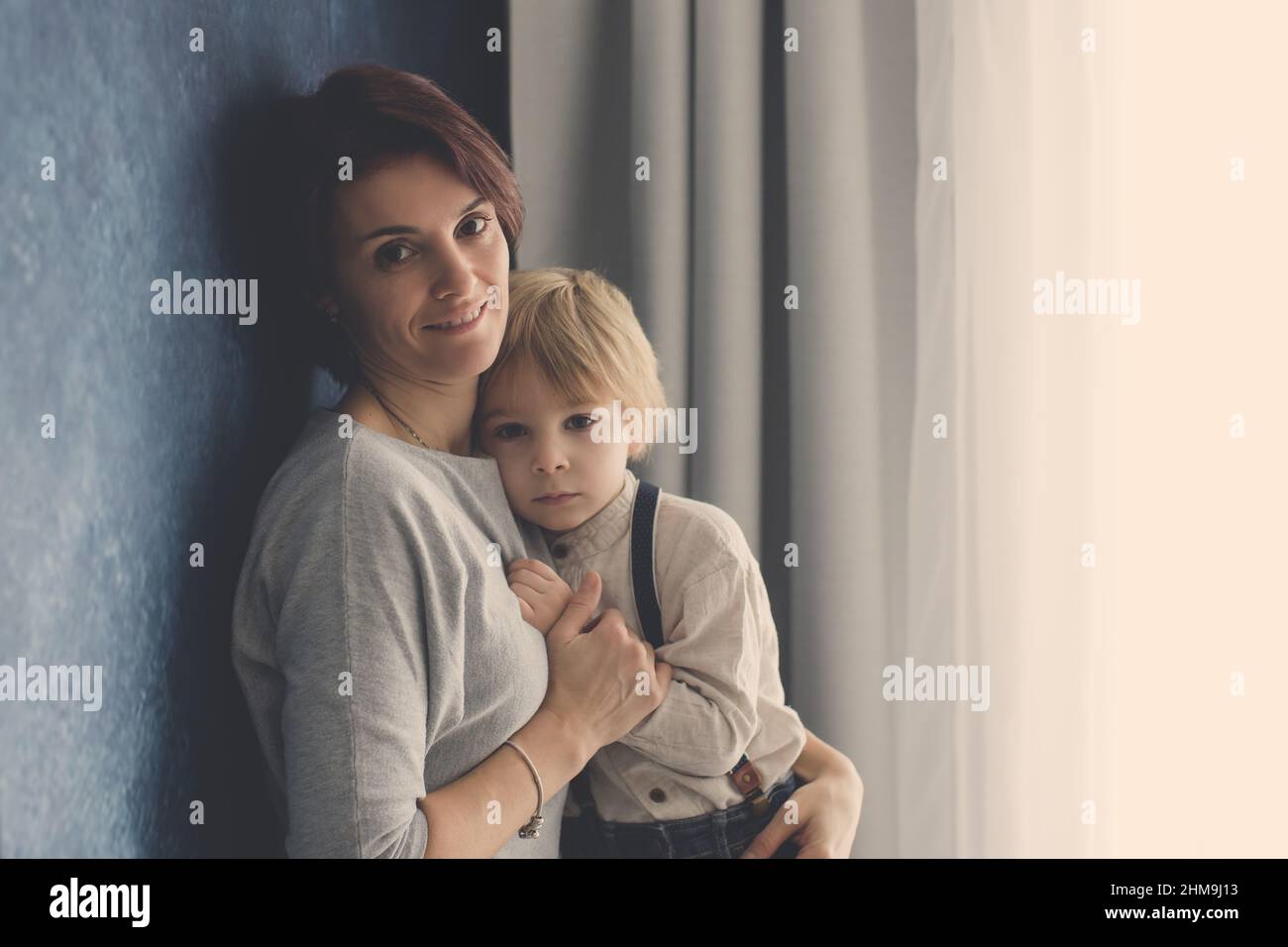 Portrait of mother and child, hugging on a back lit white background ...