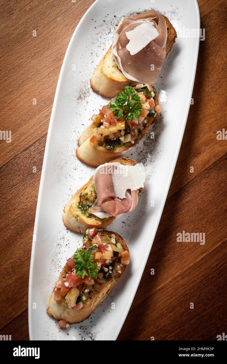 Basque Pinchos tapas with jamon serrano ham and tomato bruschetta on ...