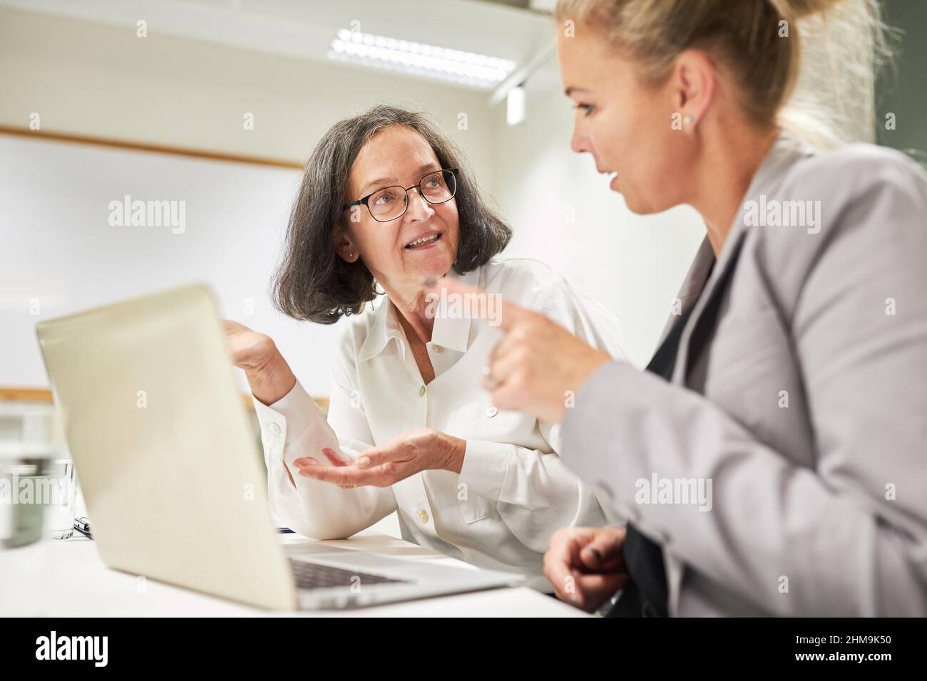 Two business women with tablet computers discussing strategy and ...