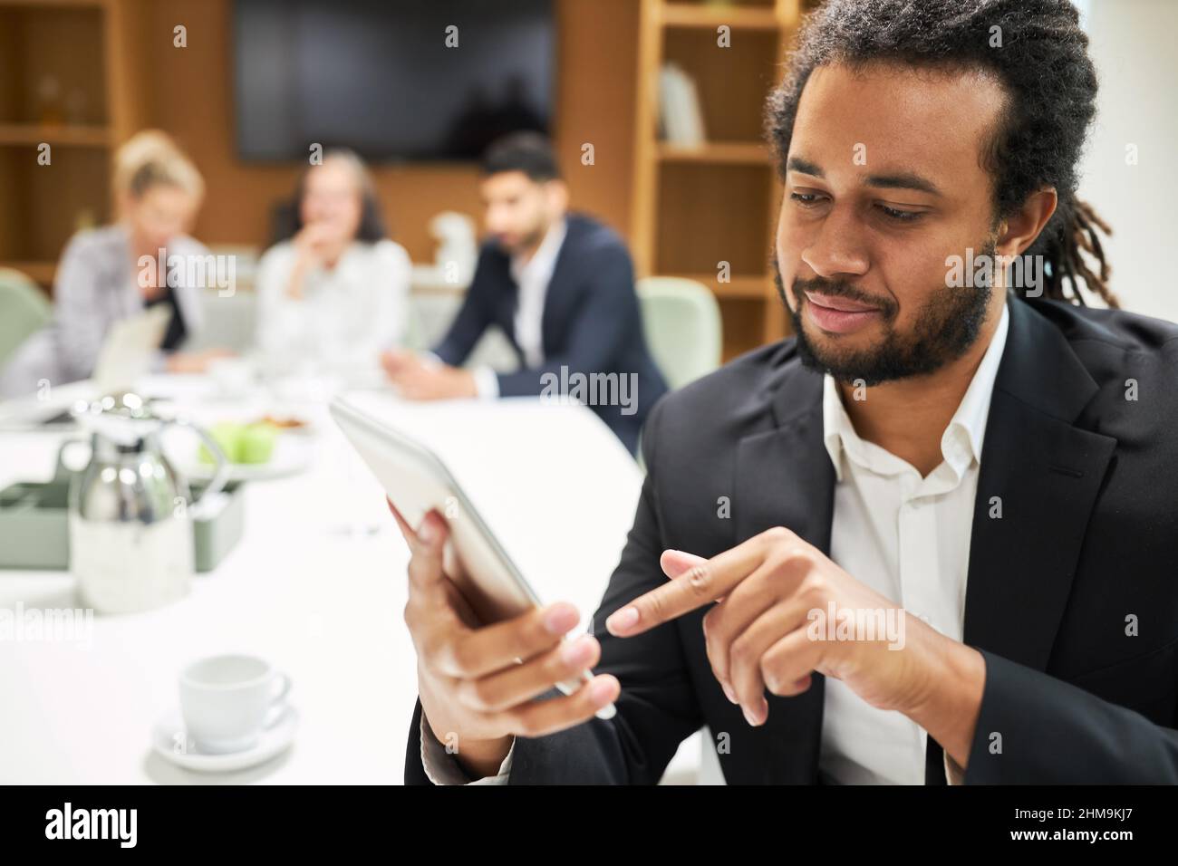 Business man typing text message on smartphone with team in conference ...