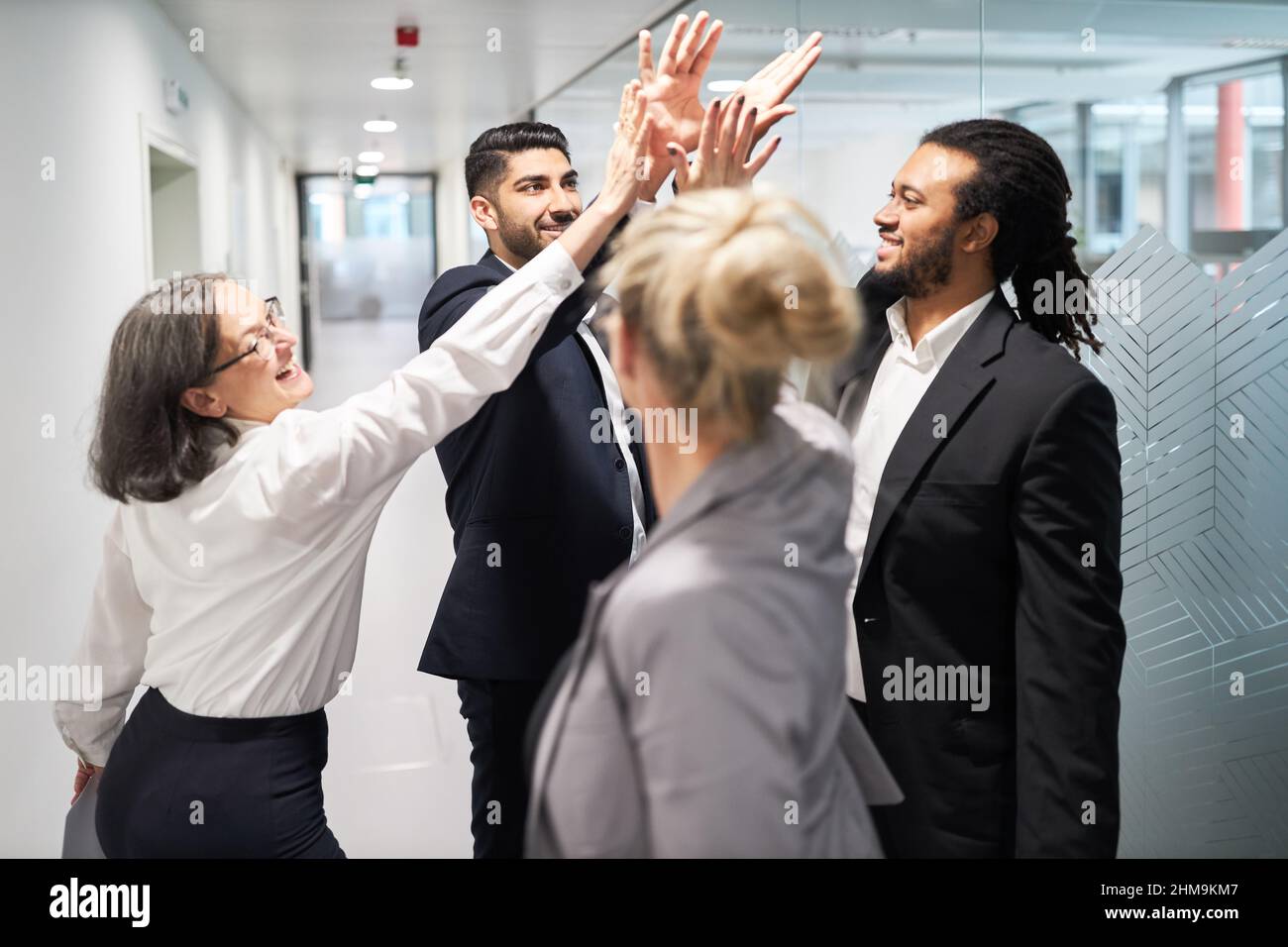 Business team people doing high five on office corridor for ...