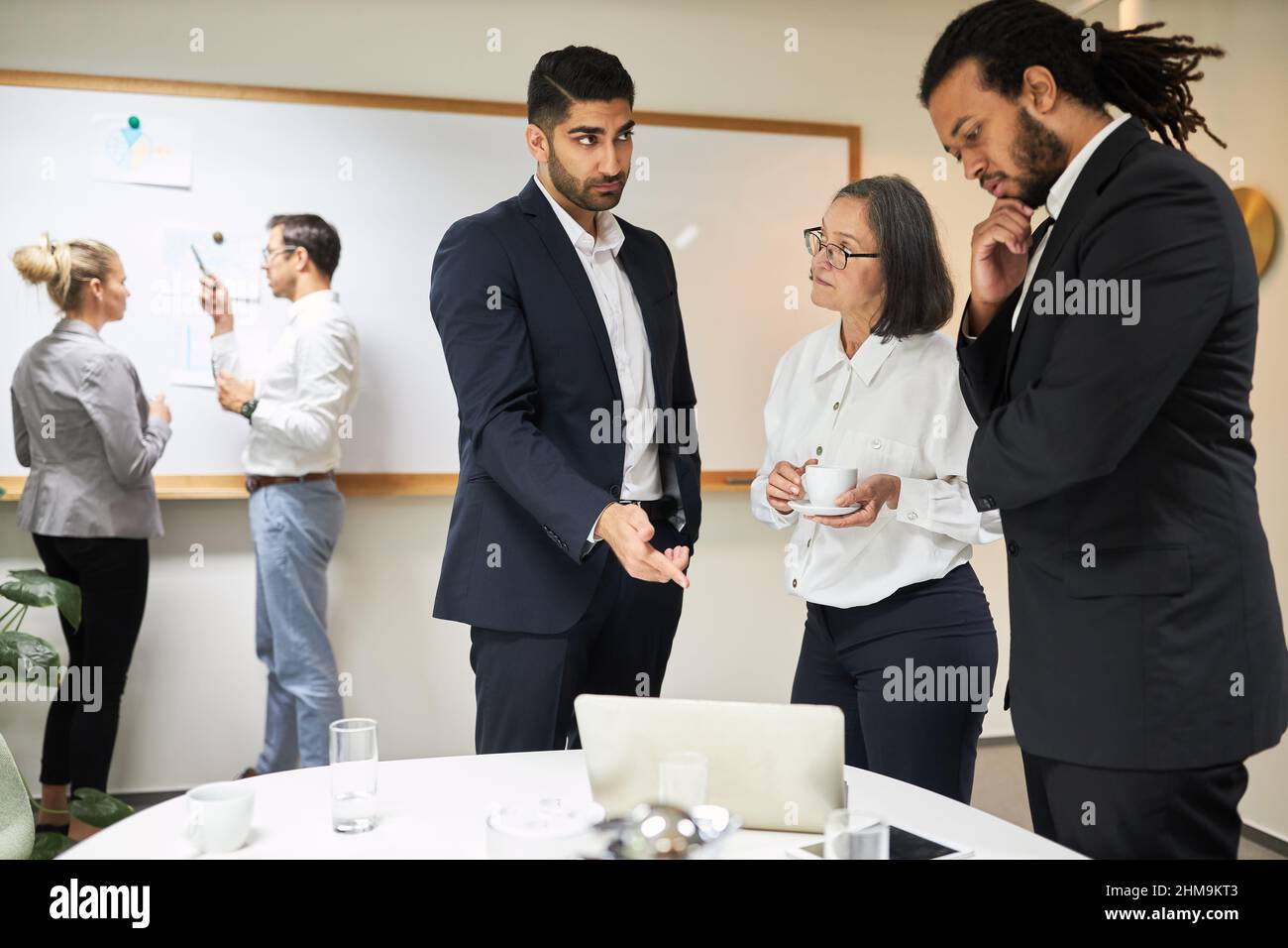 Business people in start up team discussing project on computer in ...