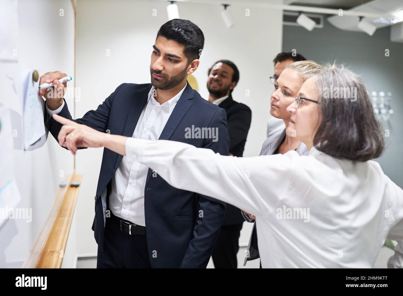 Start-up team and older businesswoman as boss at the whiteboard during ...