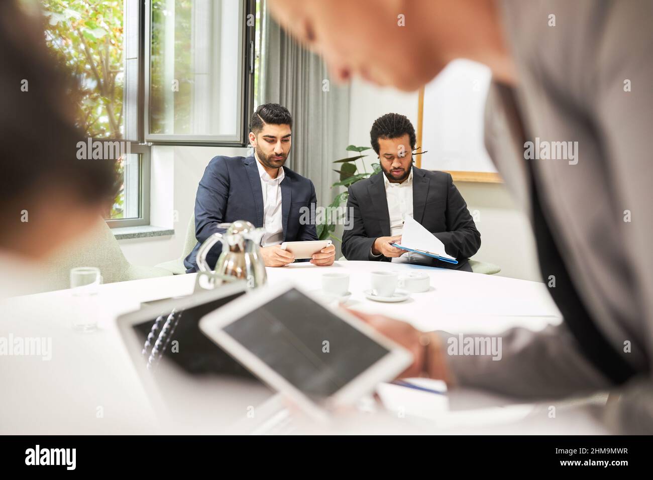 Business people working together with tablet computers in a meeting in ...
