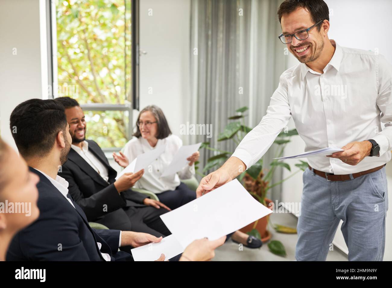 Business man as a trainer distributes questionnaires to trainees or ...