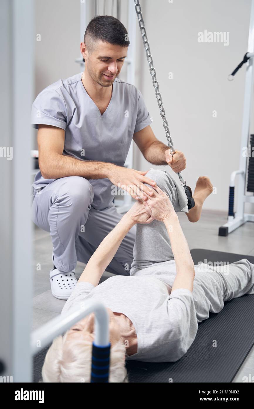Senior woman bending her knee with cable machine Stock Photo - Alamy