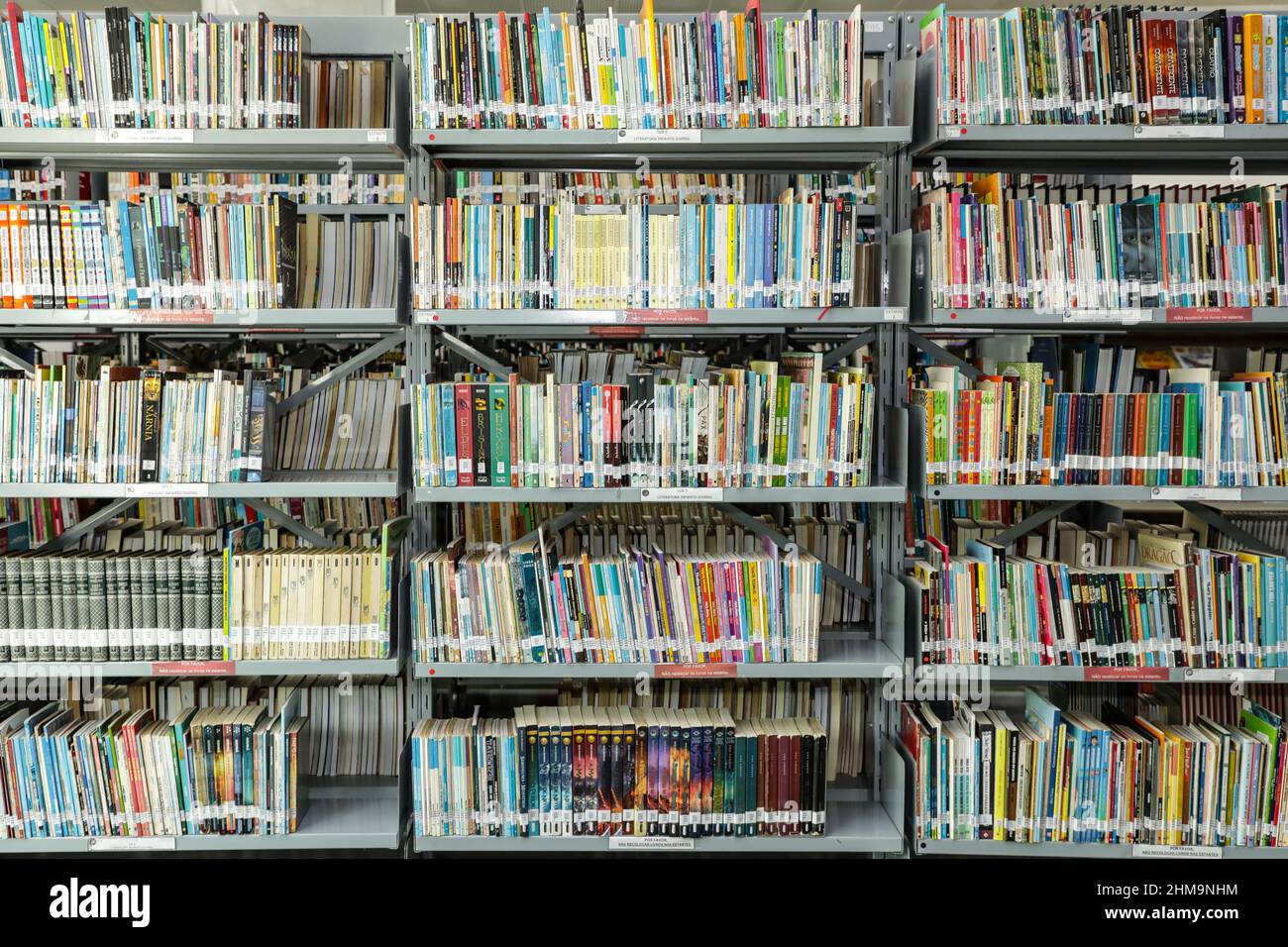 Bookshelf with several books, in multiple colors, lined up in a library ...