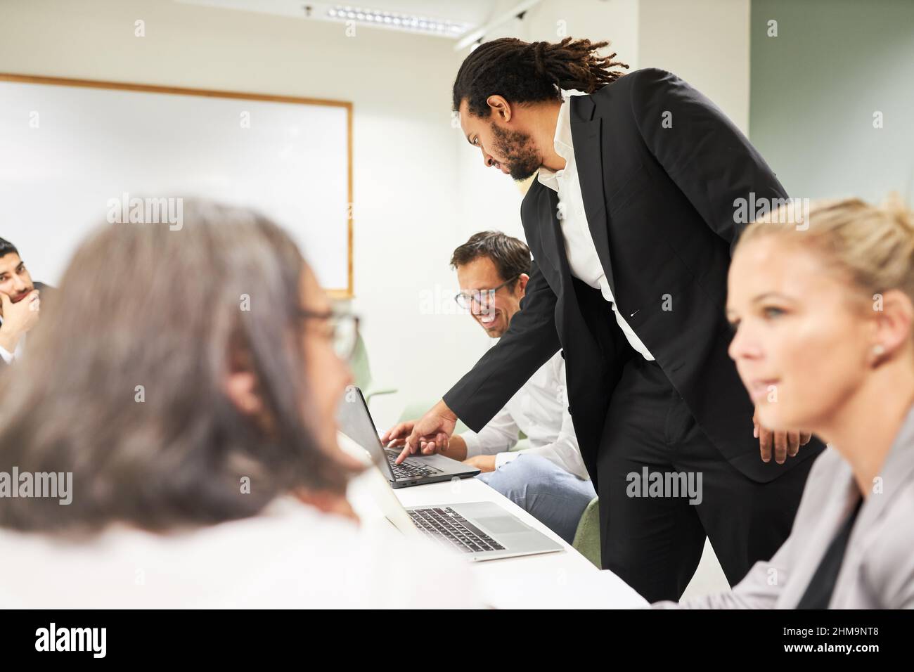 Business man as an instructor helps colleagues on the computer in a ...