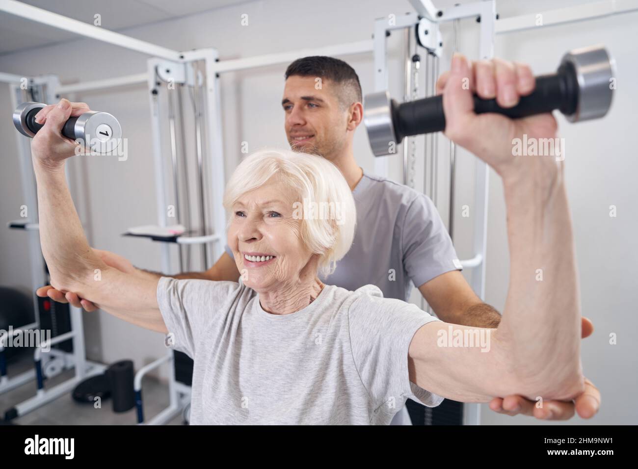 Male orthopedic surgeon doing dumbbell exercise with elderly lady Stock ...
