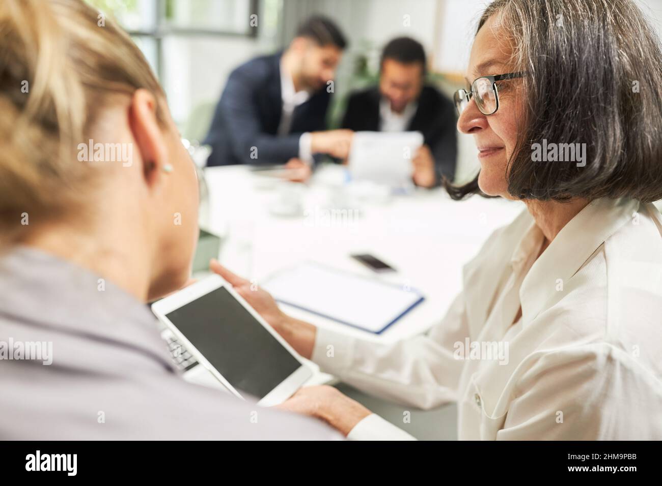 Two business women as teachers and trainees with tablet computers in a ...