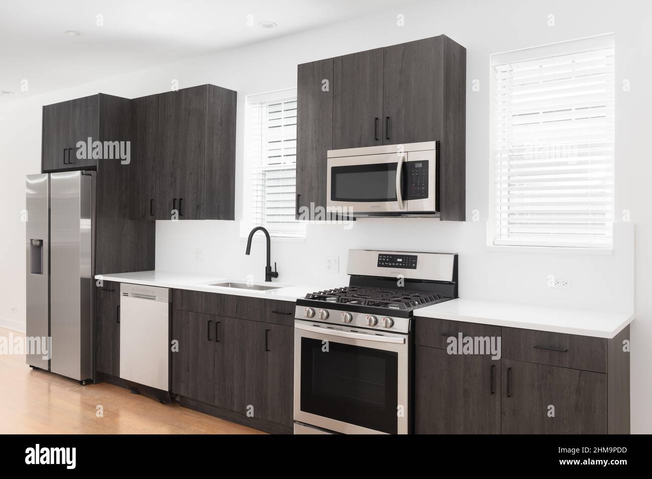 A kitchen with dark wood cabinets, stainless steel Samsung appliances ...