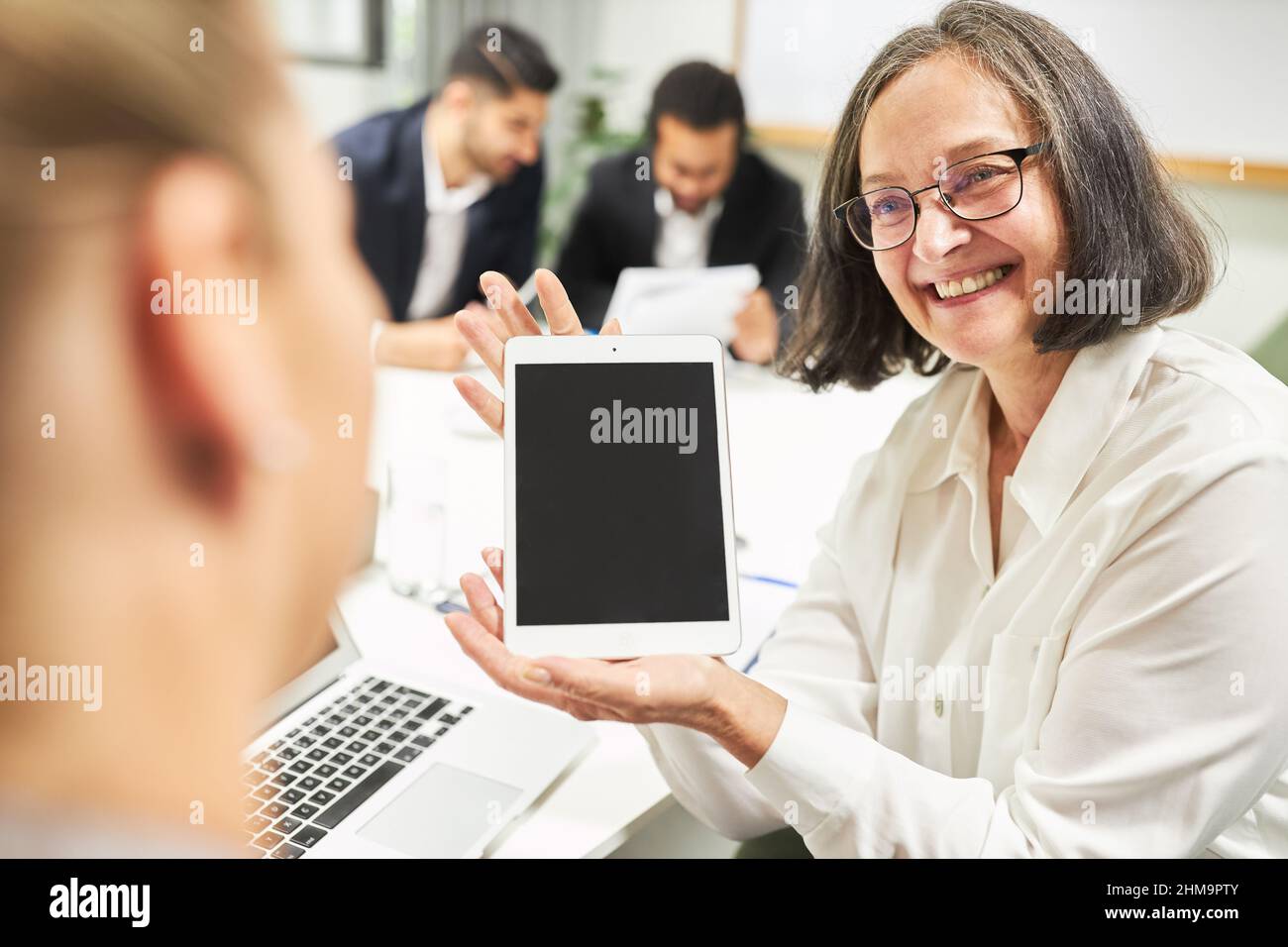Business woman as trainer or teacher shows young woman as trainee a ...