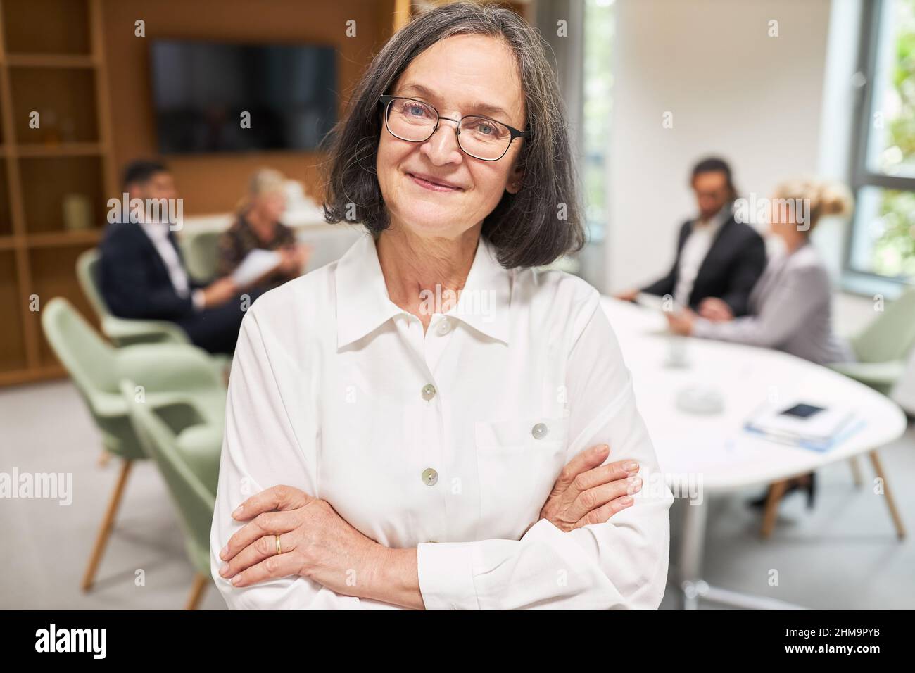 Senior business woman with crossed arms as boss or manager in ...