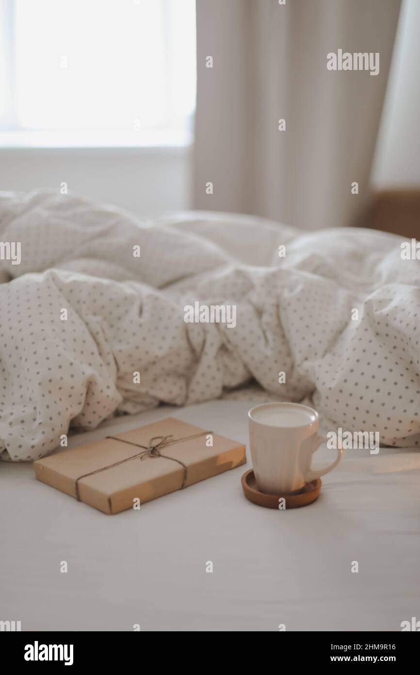 Cup of coffee with milk on the bed with white linens and blanket ...