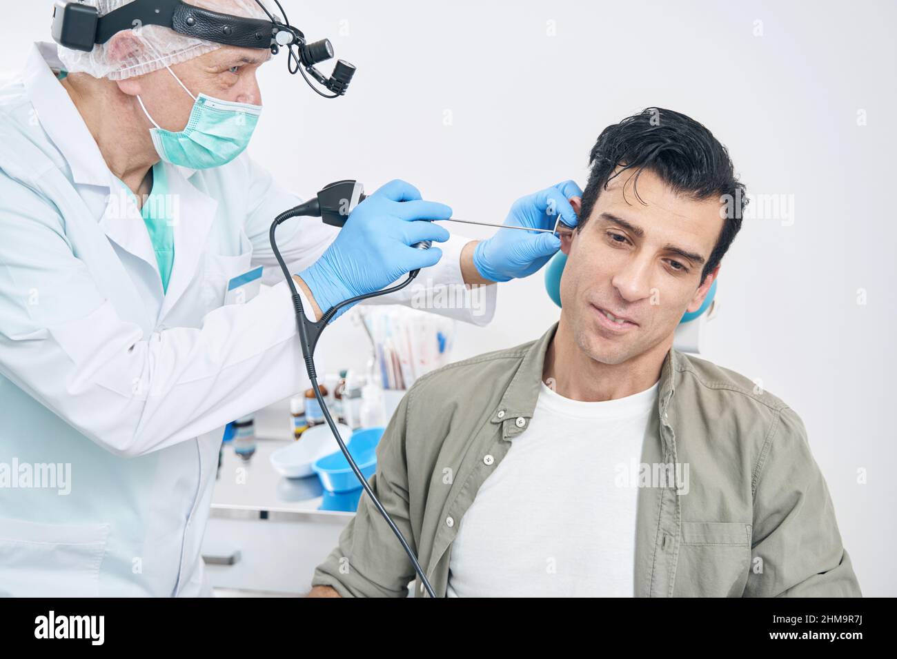 Otorhinolaryngologist examining patient with medical instrument at the ...