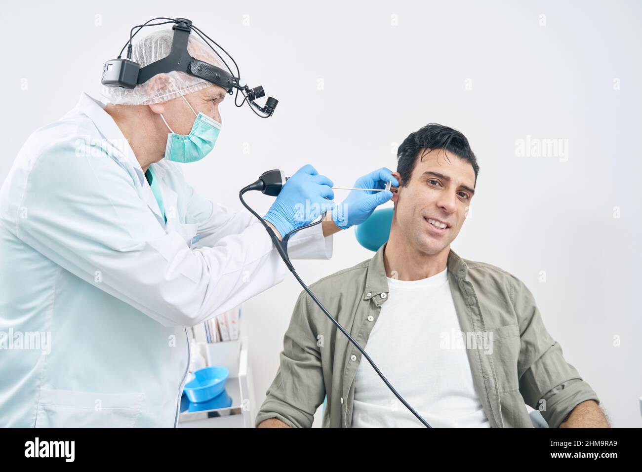 Otorhinolaryngologist examining man with medical instrument at the ...