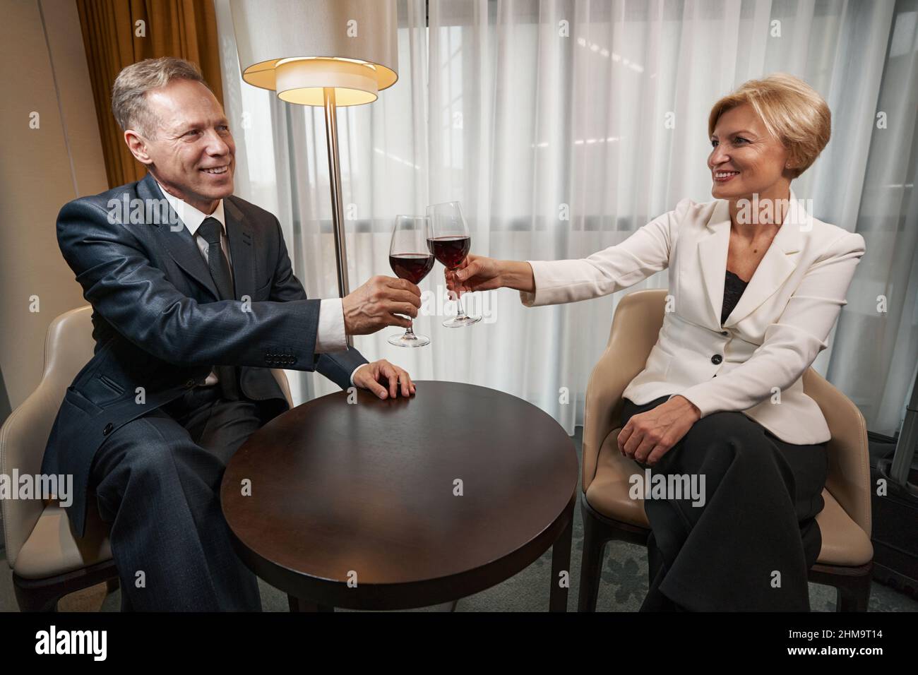 Happy business colleagues drinking wine at hotel room together Stock ...