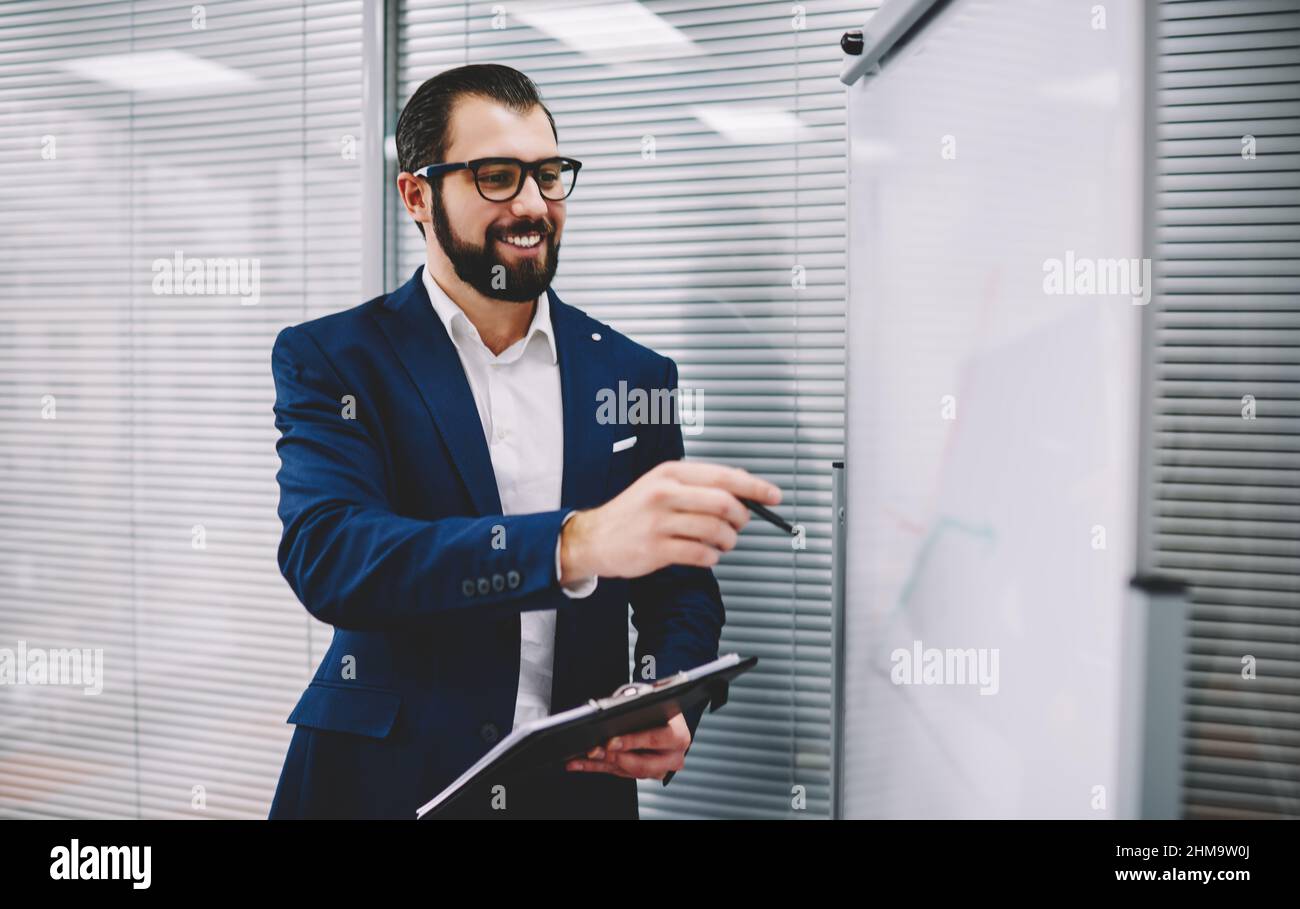 Smiling executive manager standing with documents and looking at ...