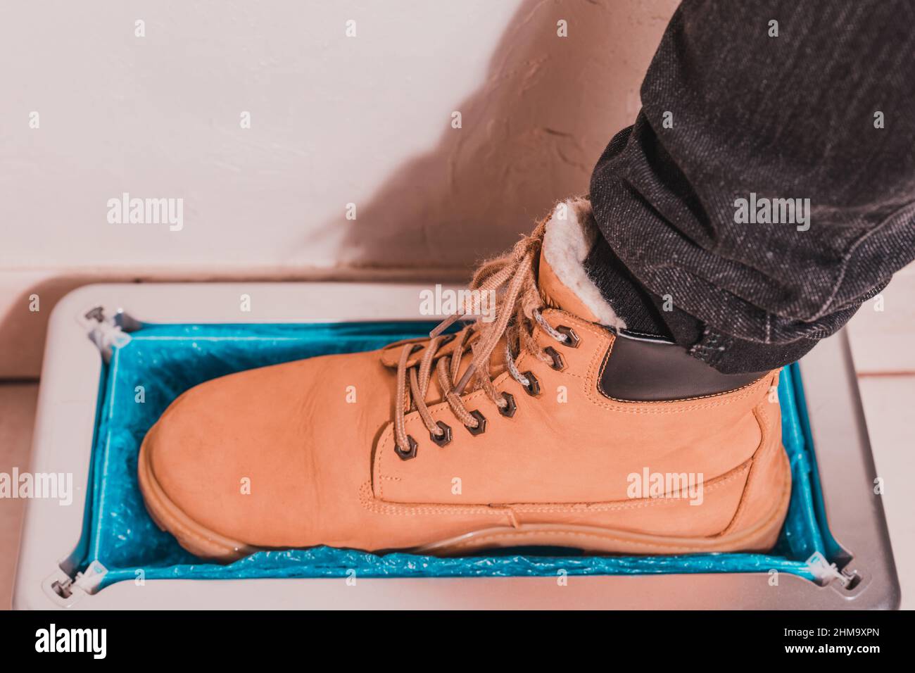 Device for automatic dressing of boot covers, a man in brown shoes puts ...