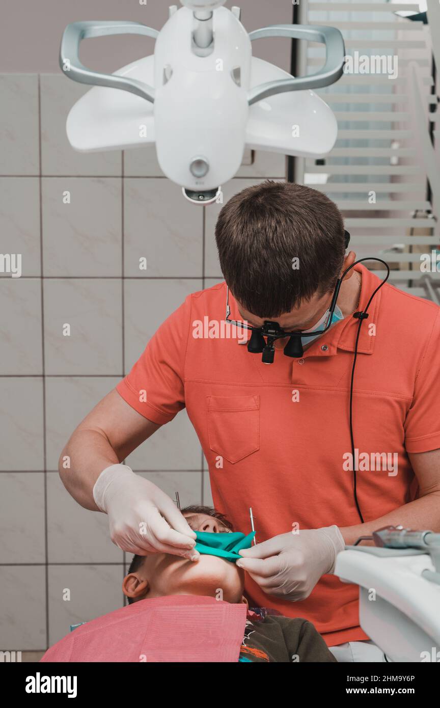 The dentist installs a rubber dam and a clamp for the treatment of a ...