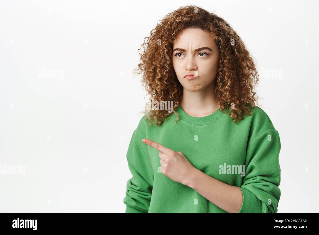 Annoyed curly girl student, frowning and sulking bothered, pointing and ...
