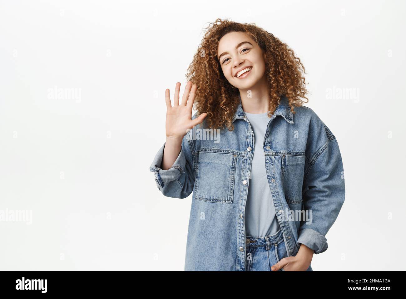 Friendly young modern woman wave hand, saying hello, greeting with hi ...
