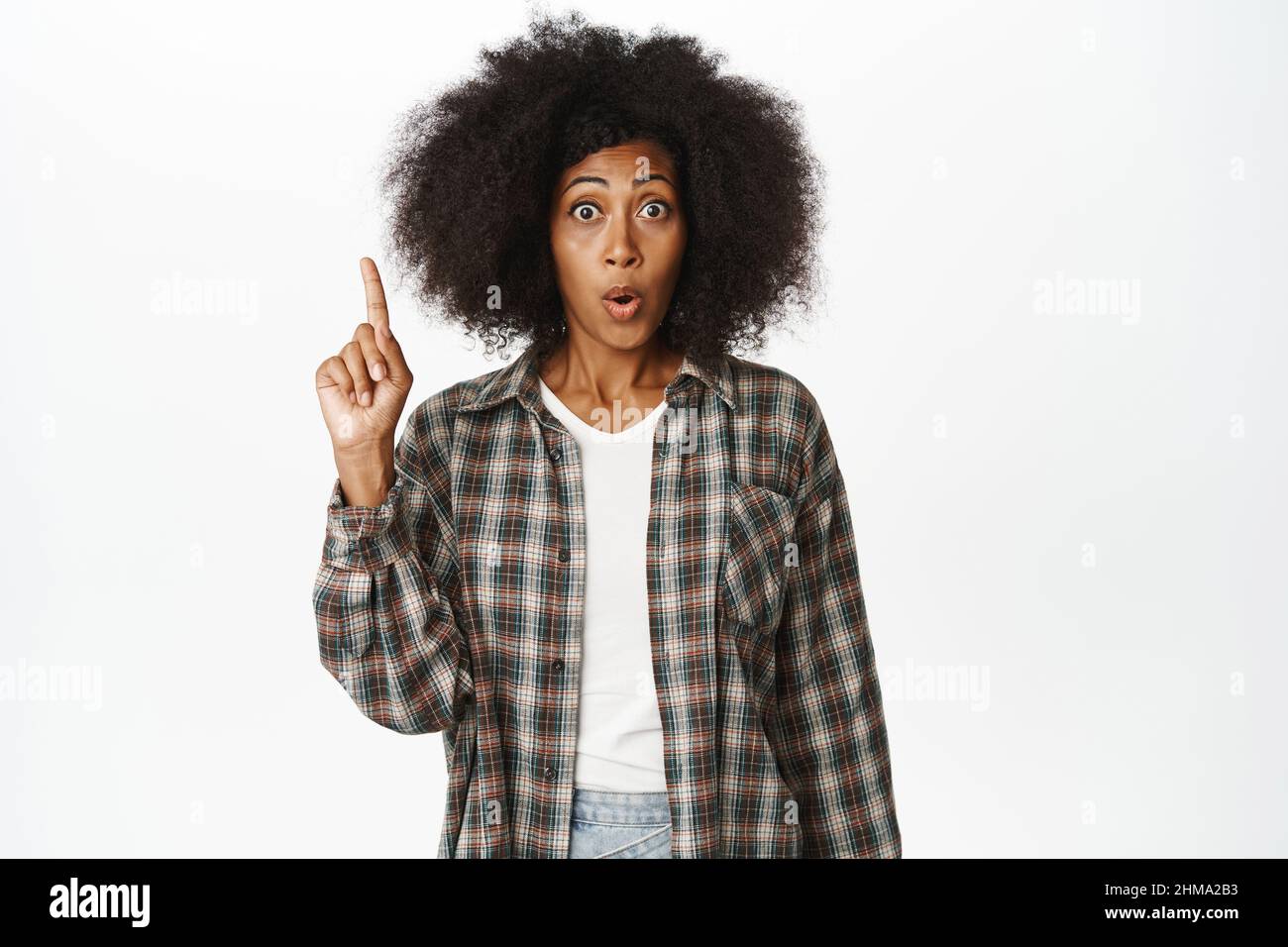 Enthusiastic african american woman pointing finger up, looking ...