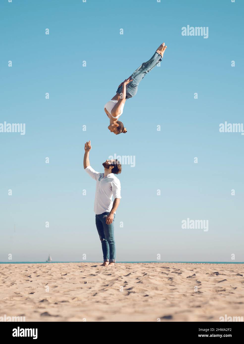 Full body side view of sporty female acrobat performing somersault high ...