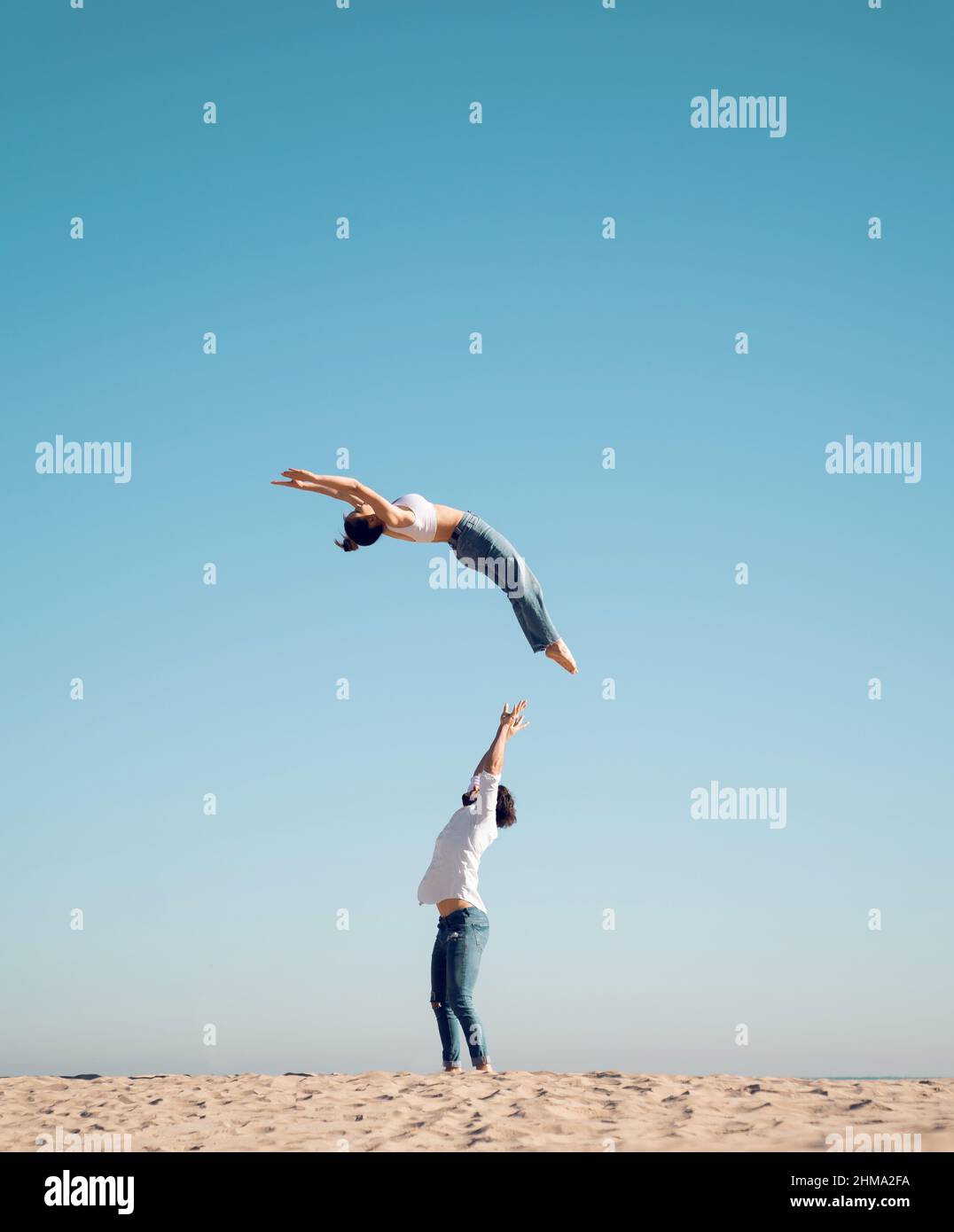 Full body side view of sporty female acrobat performing somersault high ...