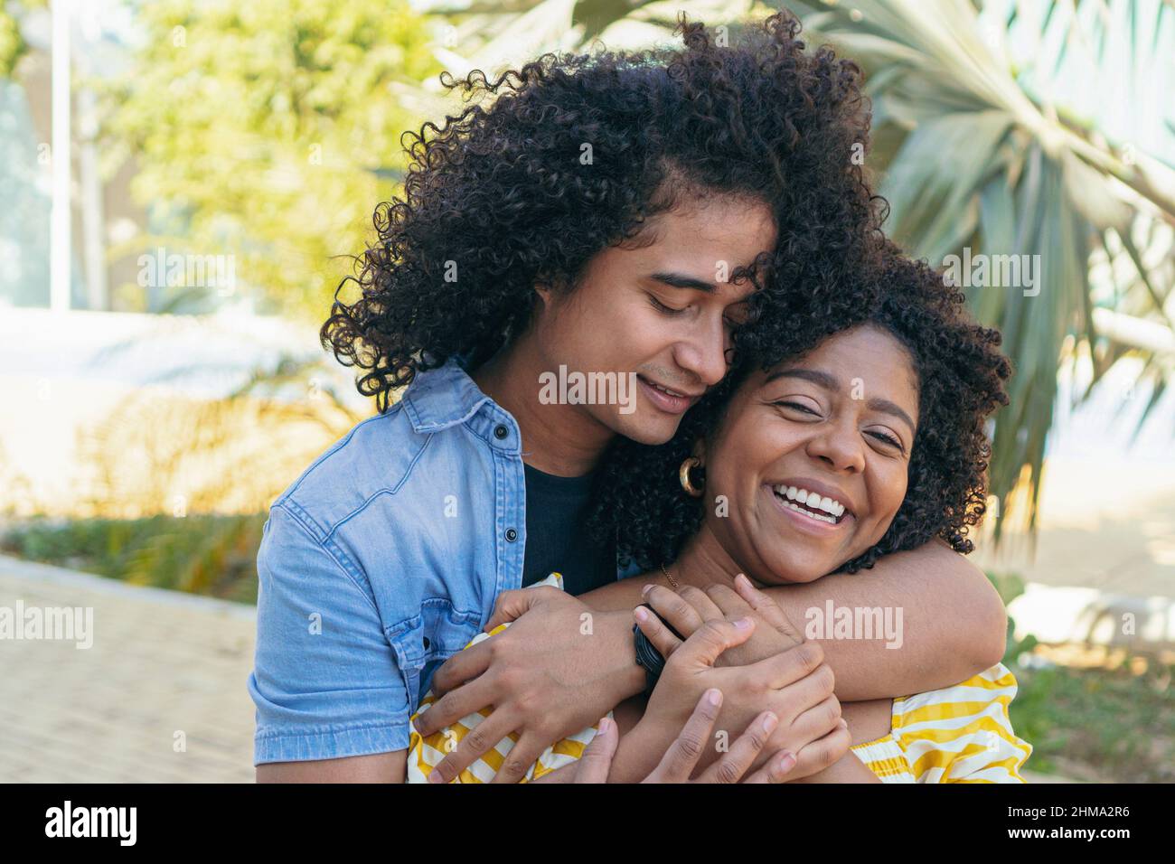 Hispanic boyfriend laughing with closed eyes while embracing smiling ...