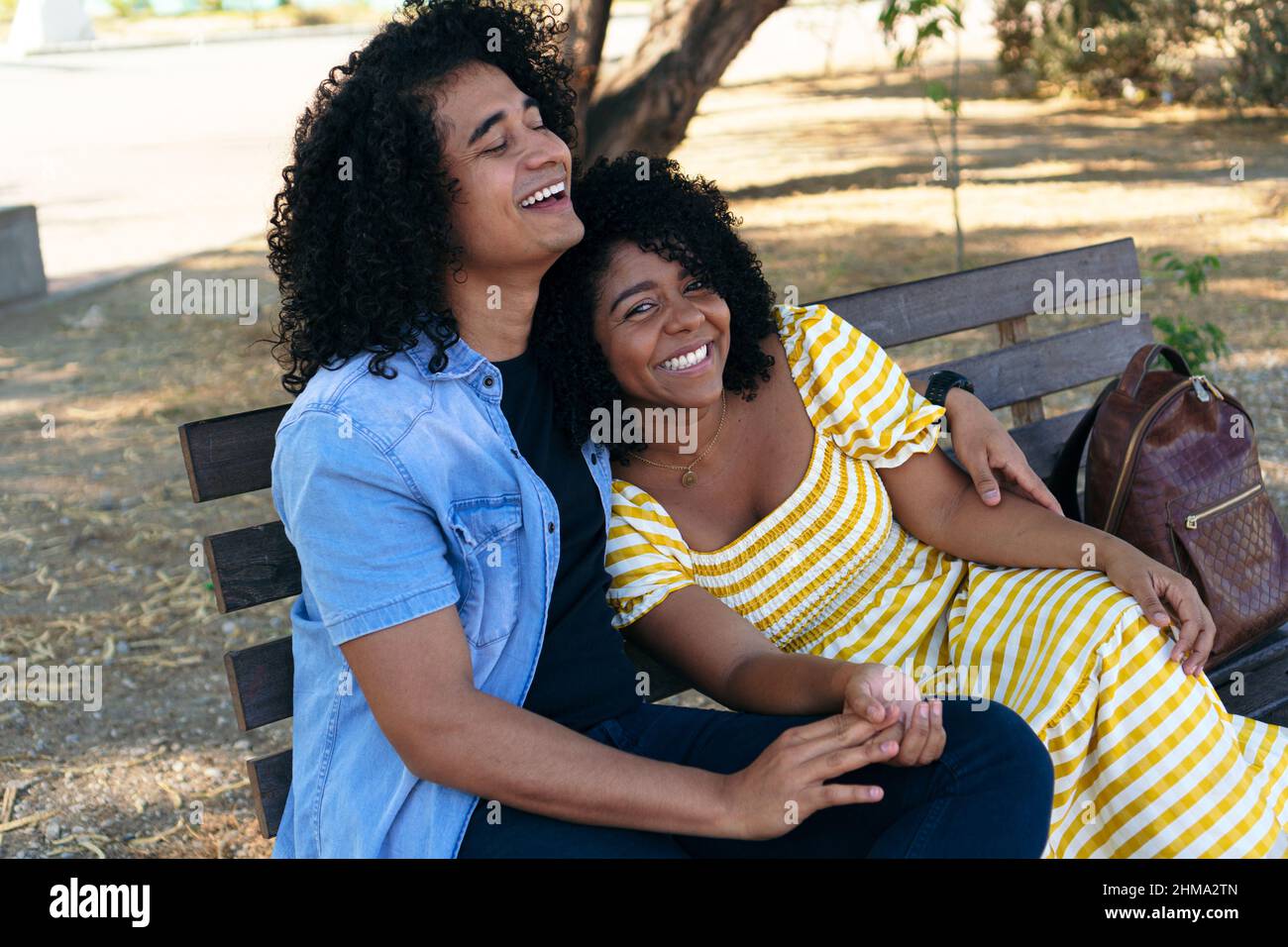 Hispanic boyfriend laughing with closed eyes while embracing smiling ...